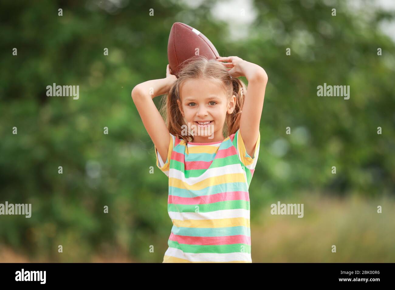Portrait of cute little girl with rugby ball outdoors Stock Photo - Alamy