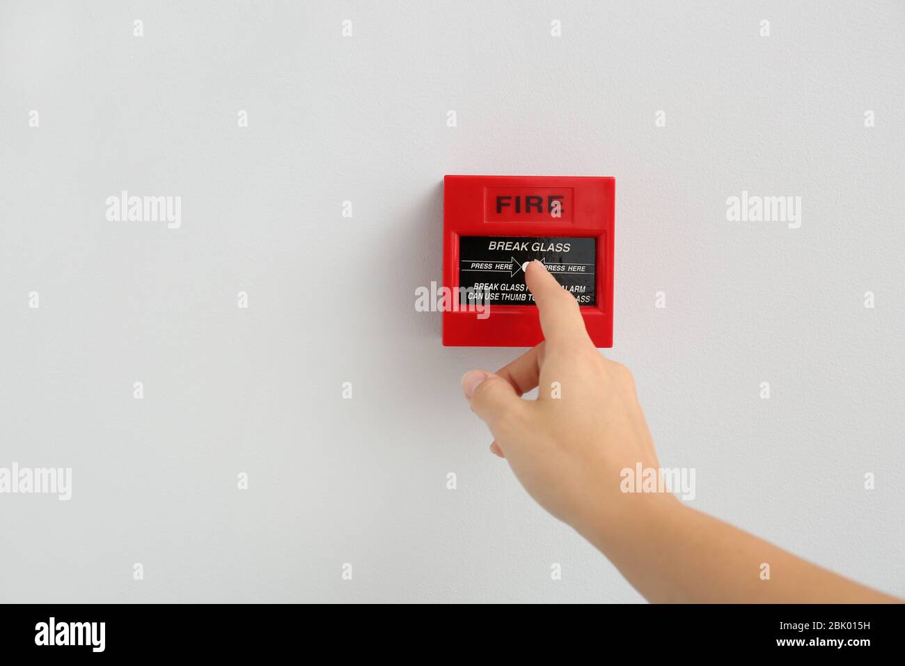 Woman using manual call point of fire alarm system Stock Photo - Alamy