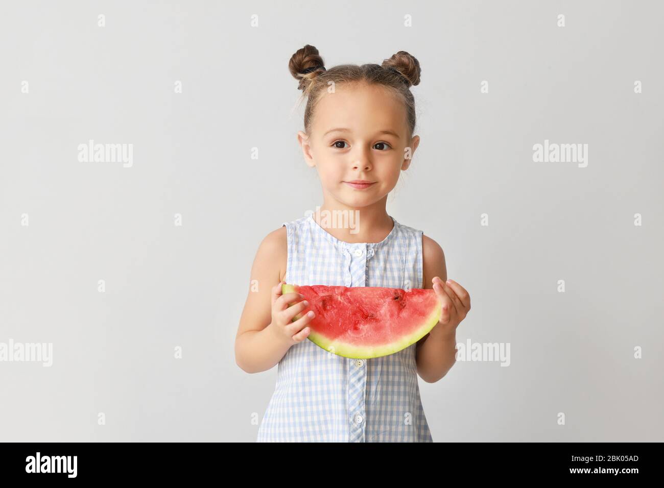 Cute little girl with slice of fresh watermelon on light background ...
