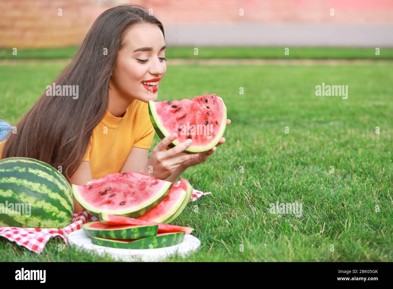Beautiful young woman eating sweet watermelon in park Stock Photo - Alamy
