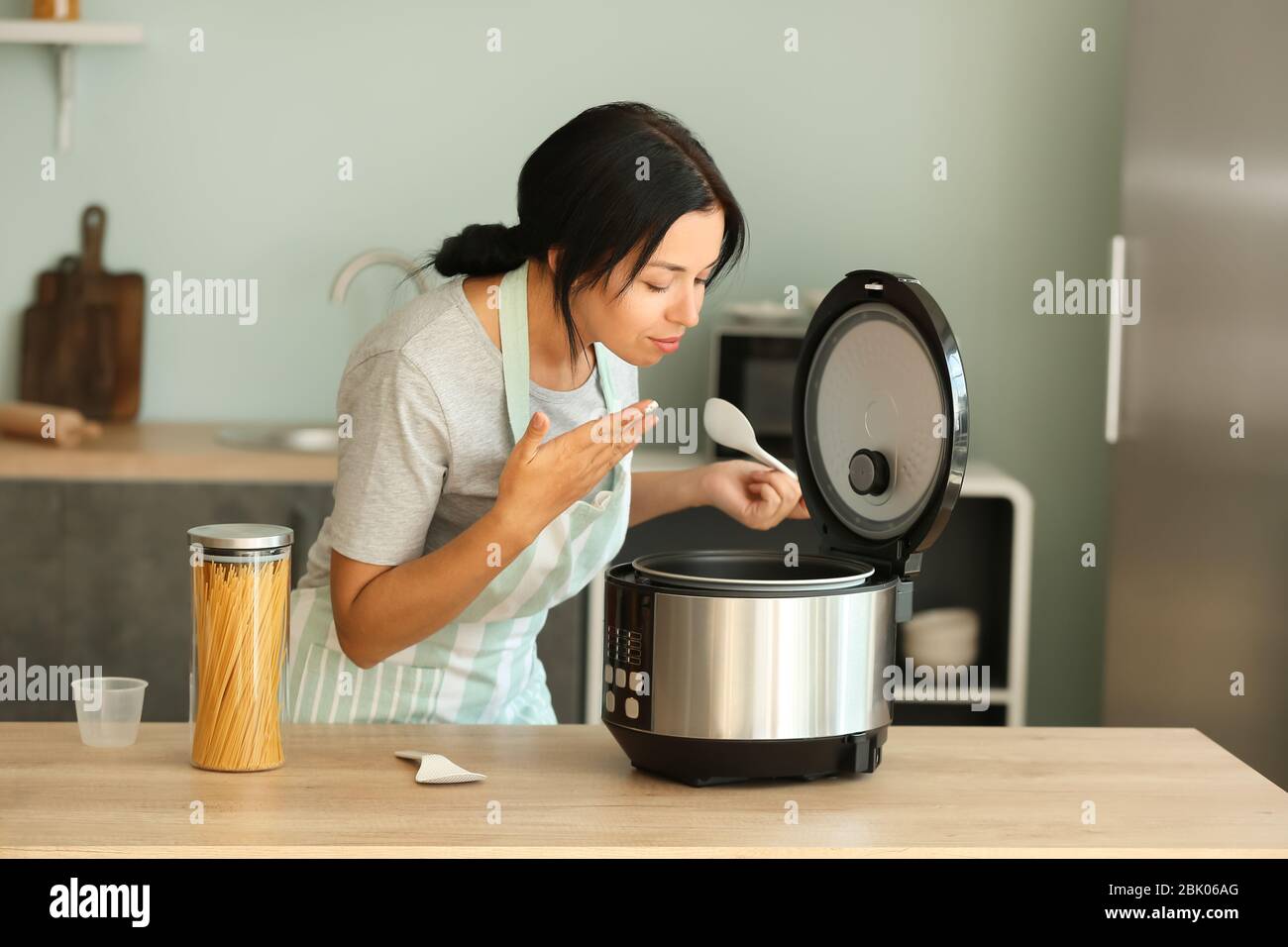 Beautiful woman using multi cooker at home Stock Photo - Alamy