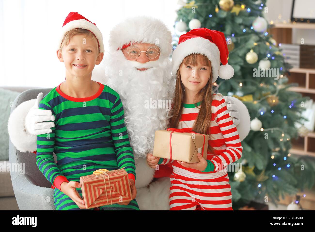 Santa Claus and his little helpers with gifts in room decorated for ...