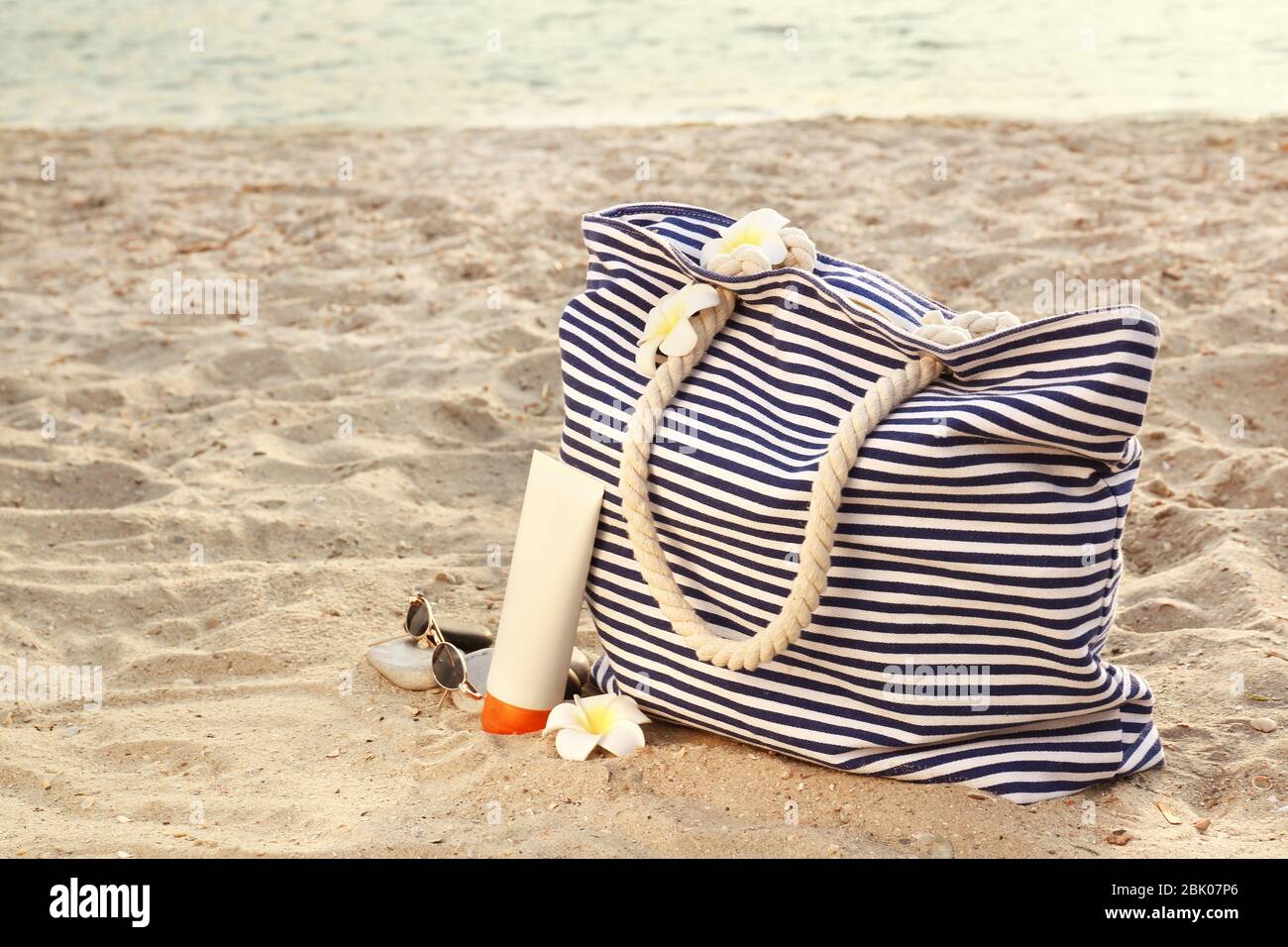 Bag with sunscreen cream and sunglasses on sand beach Stock Photo - Alamy