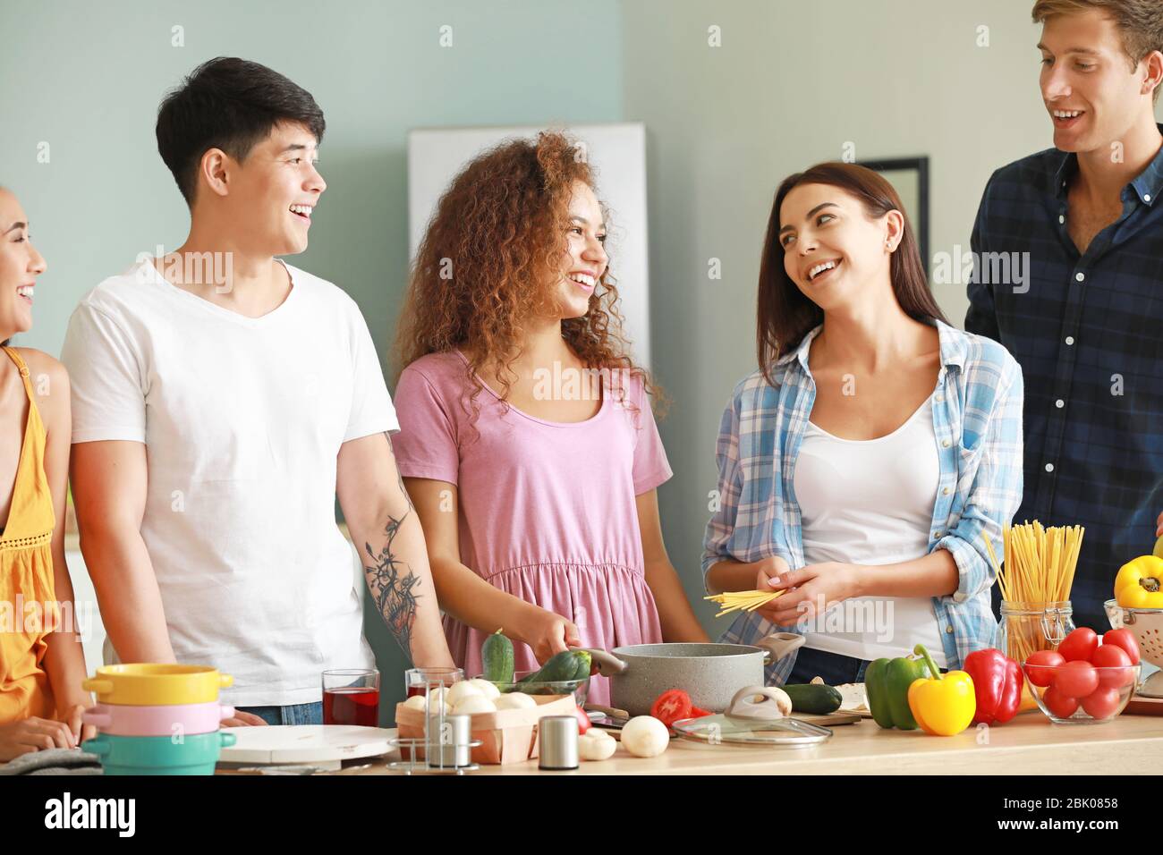 Happy friends cooking together in kitchen Stock Photo - Alamy