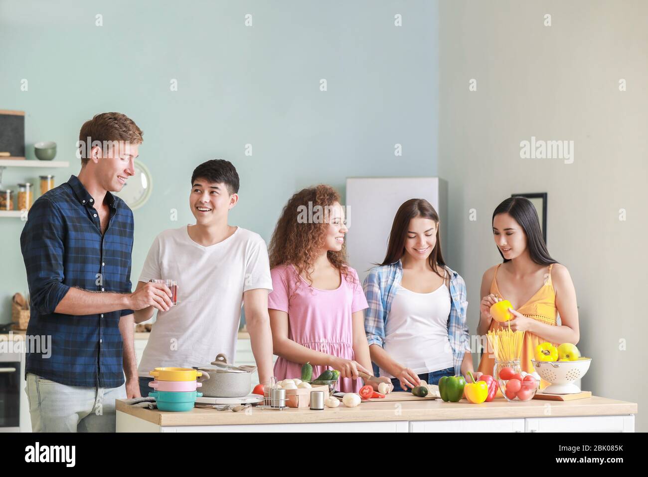 Happy friends cooking together in kitchen Stock Photo - Alamy