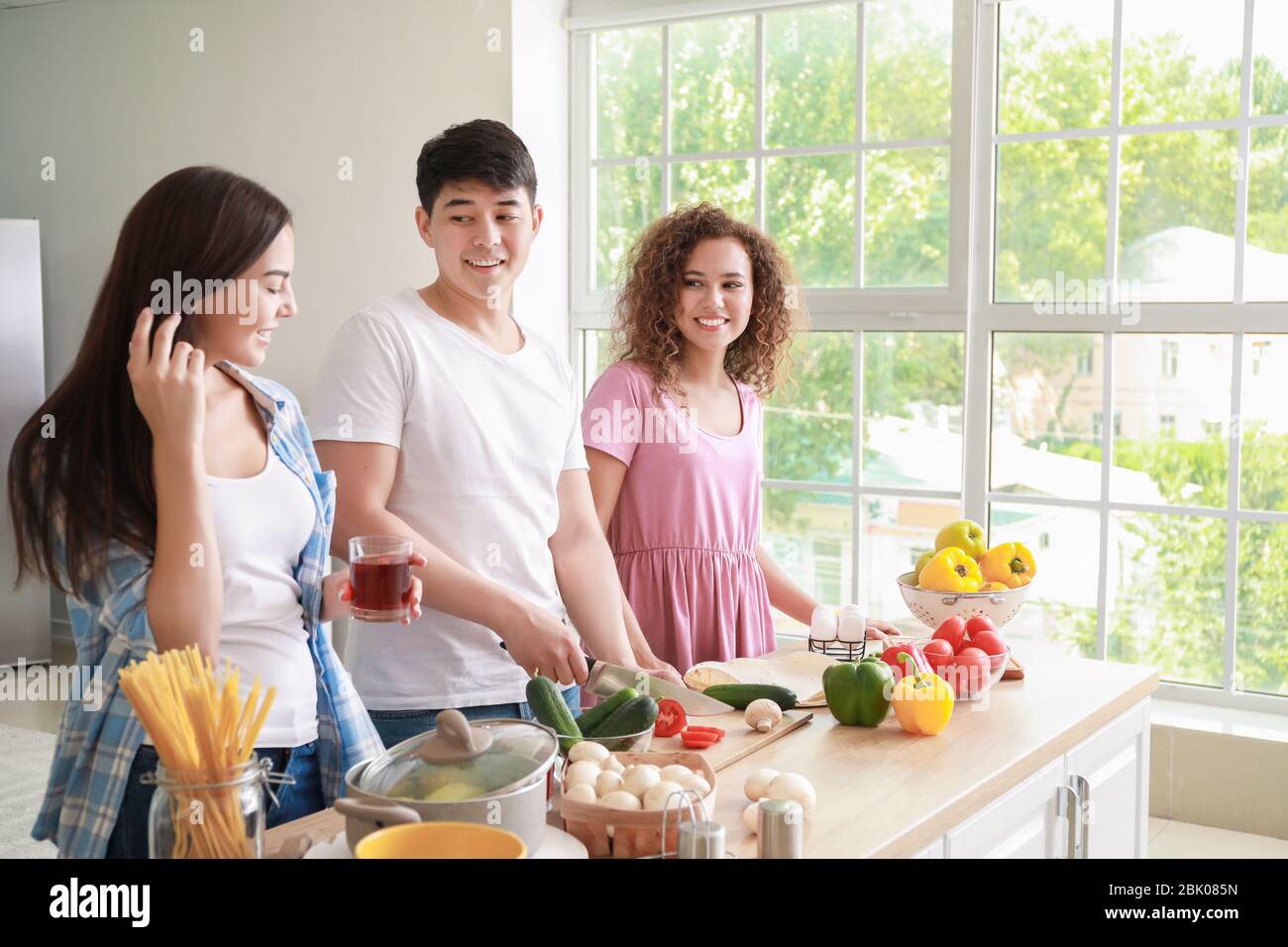 Happy friends cooking together in kitchen Stock Photo - Alamy