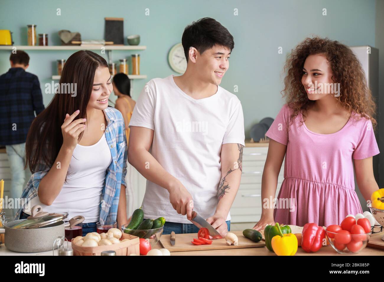 Happy friends cooking together in kitchen Stock Photo - Alamy