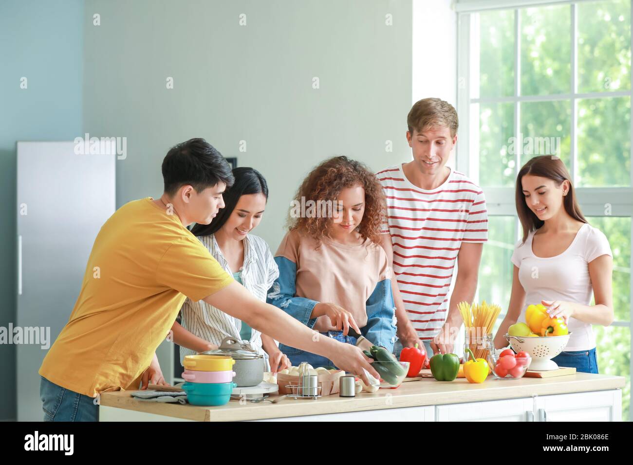 Happy friends cooking together in kitchen Stock Photo - Alamy