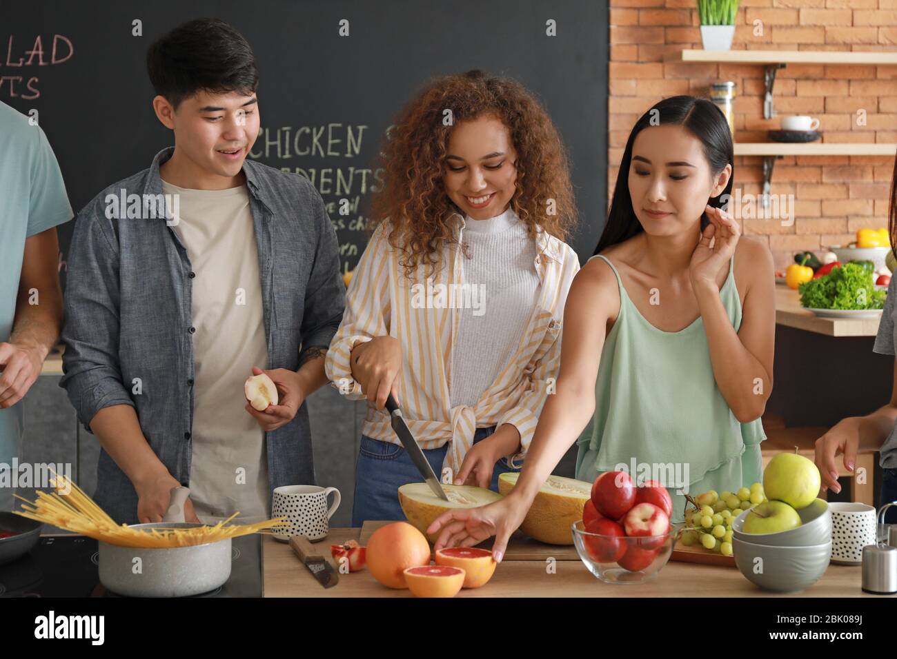 Happy friends cooking together in kitchen Stock Photo - Alamy
