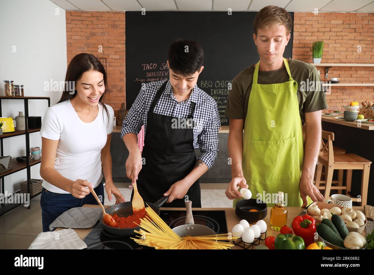 Happy friends cooking together in kitchen Stock Photo - Alamy