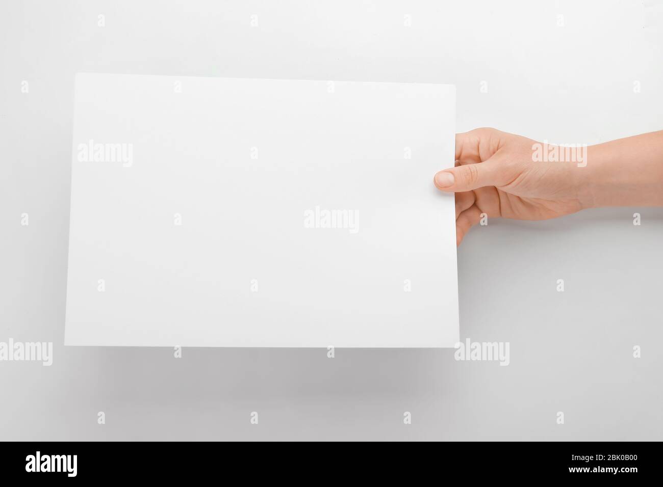 Female hand with empty sheet of paper on white background Stock Photo ...