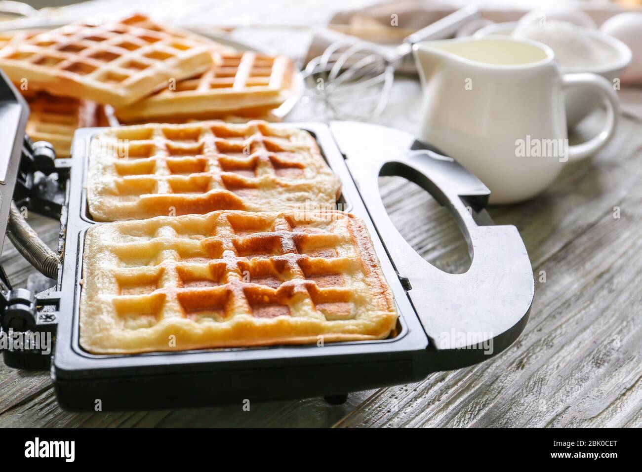 Modern maker with waffles on wooden table, closeup Stock Photo - Alamy