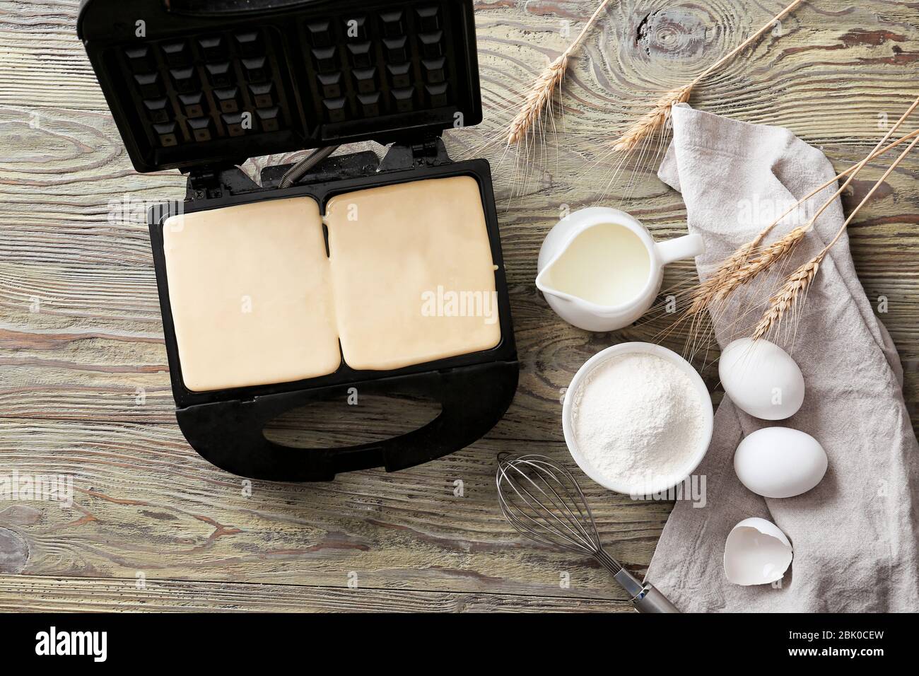 Modern waffle maker with ingredients on wooden table Stock Photo - Alamy