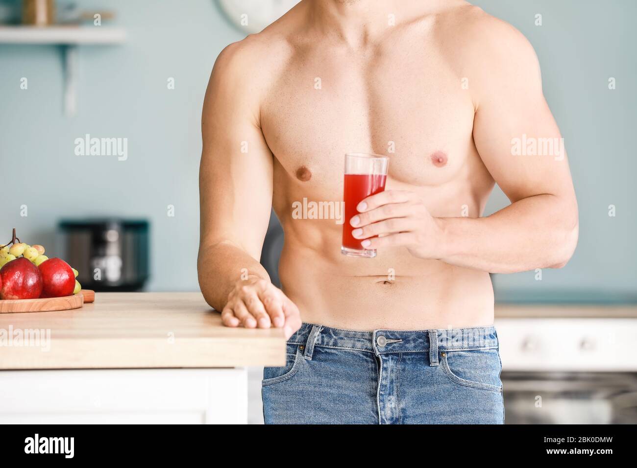 Handsome muscular man drinking juice in kitchen. Weight loss concept ...