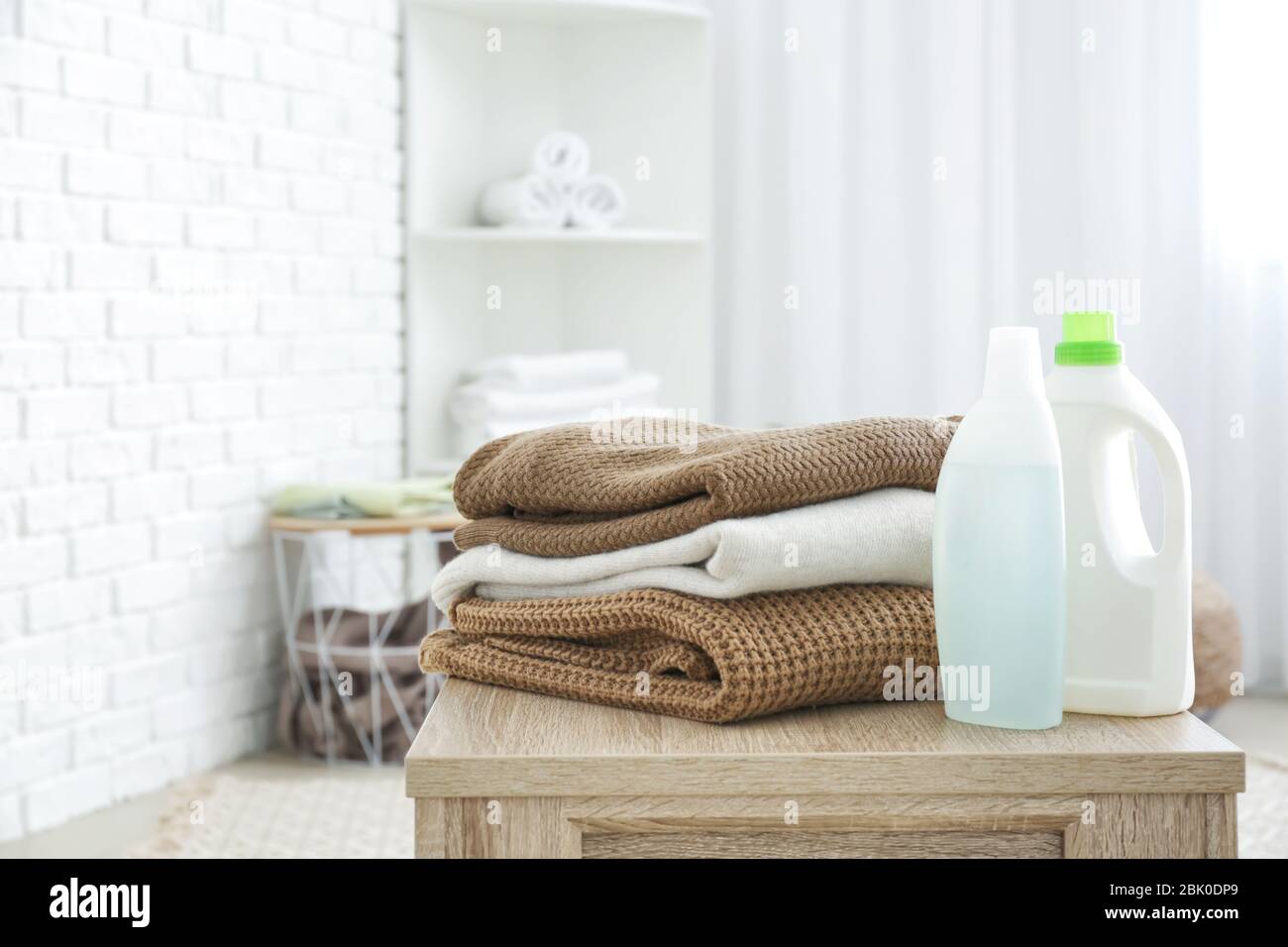 Stack of clean clothes and washing agents on table in bathroom Stock ...