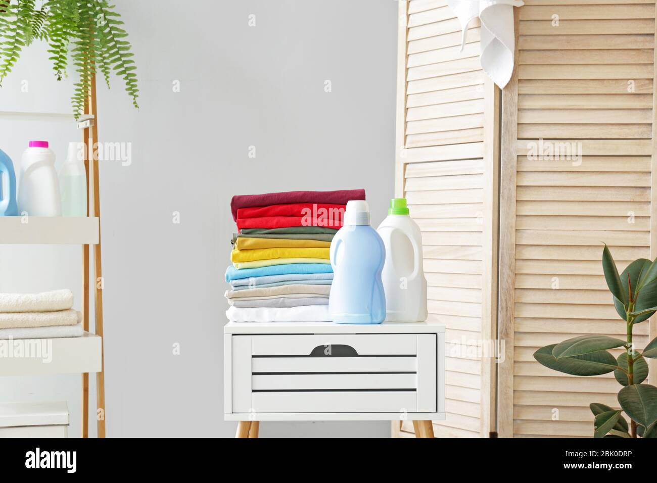 Stack of clean laundry and washing agents on table in bathroom Stock ...