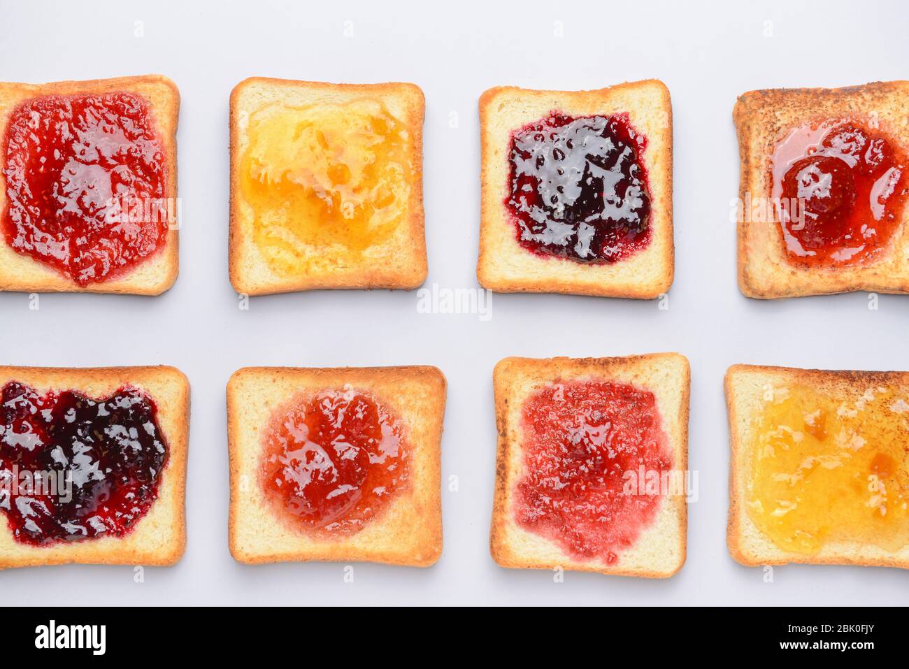 Tasty toasted bread with different jams on white background Stock Photo ...