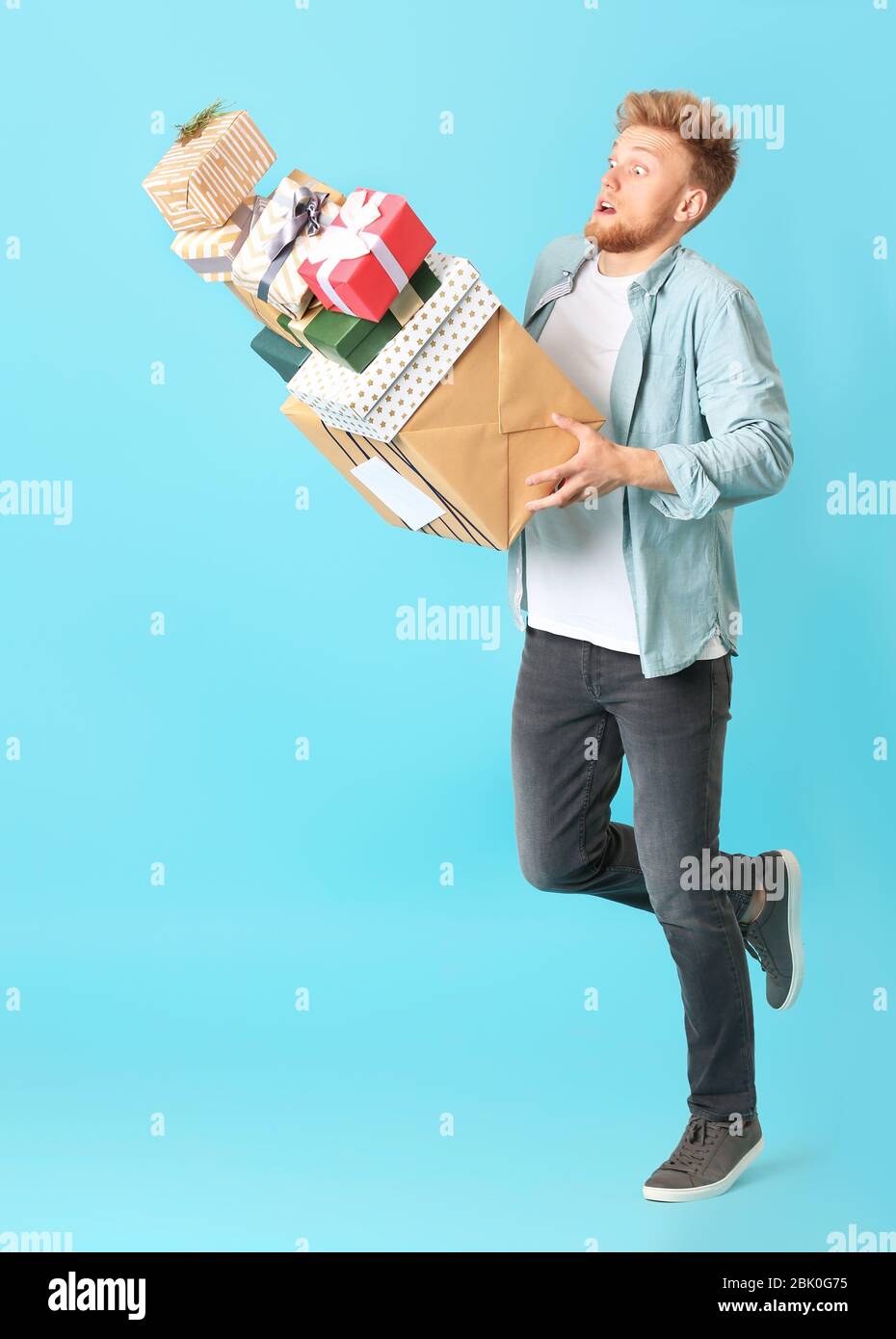 Clumsy young man dropping gift boxes on color background Stock Photo ...