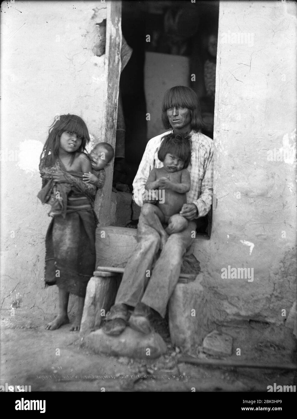 Hopi Indian father sitting in the wood framed doorway of his adobe ...