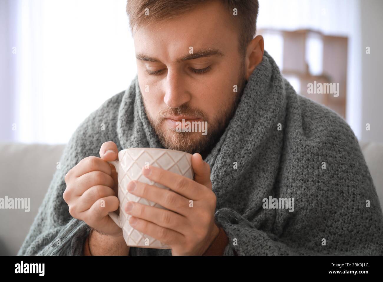 Sick man drinking hot tea at home Stock Photo - Alamy