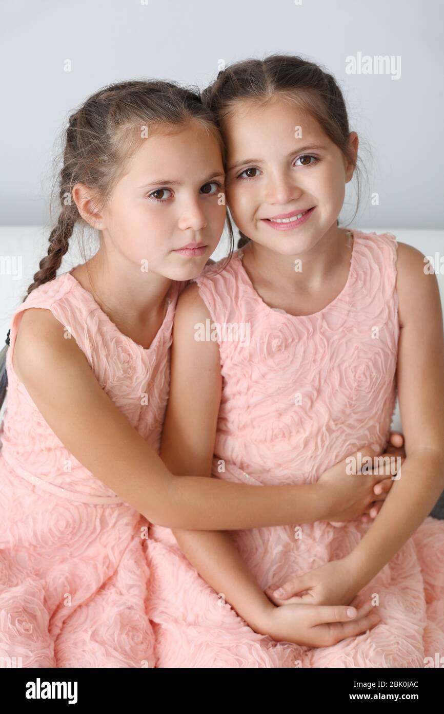 Portrait of cute twin girls on light background Stock Photo - Alamy