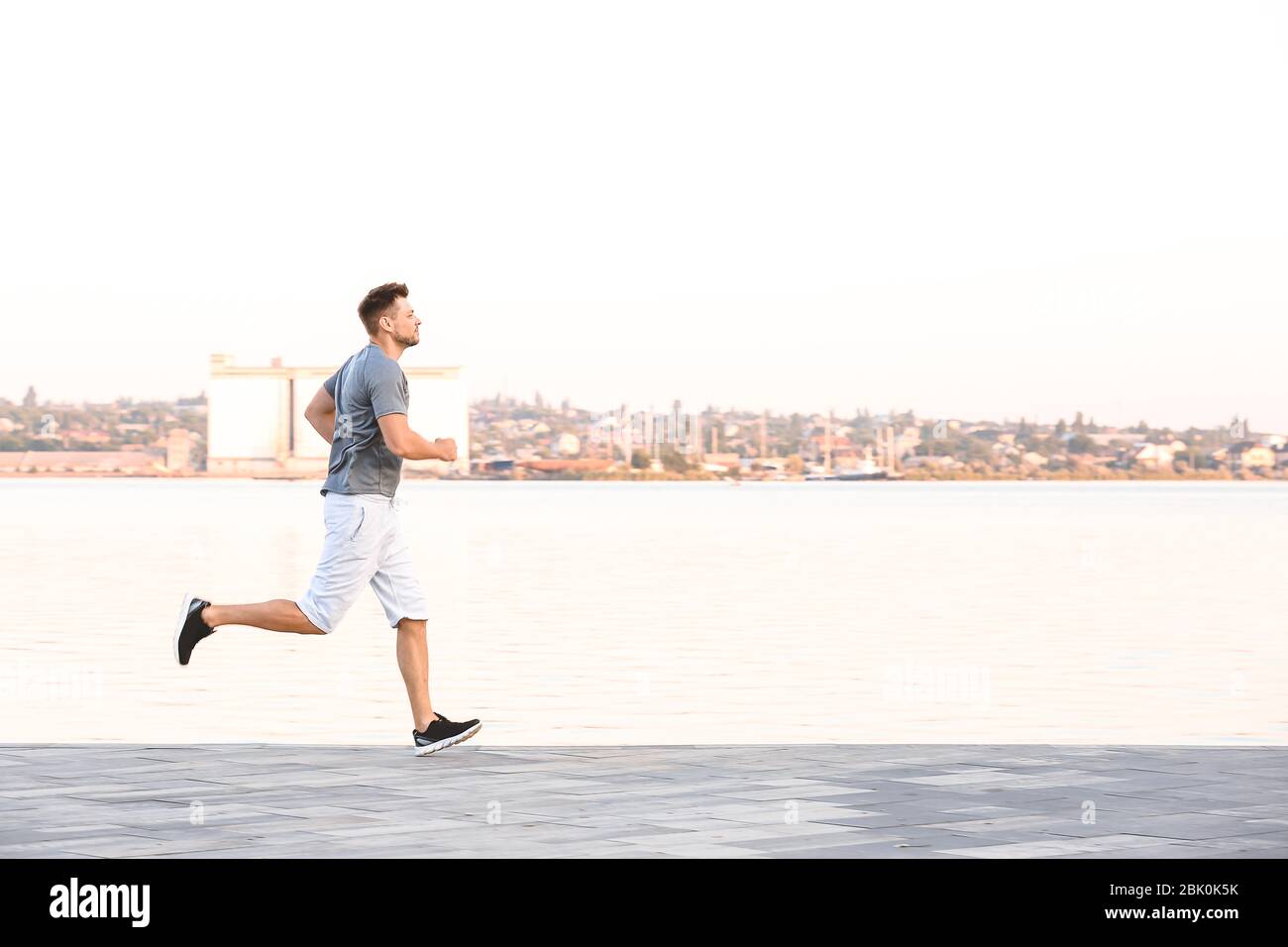 Handsome sporty man running near river Stock Photo - Alamy