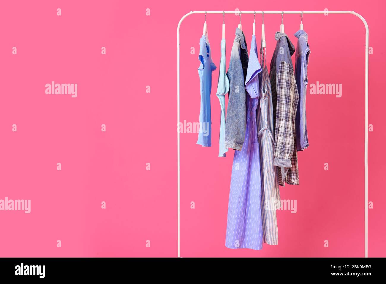 Rack with hanging clothes on color background Stock Photo - Alamy
