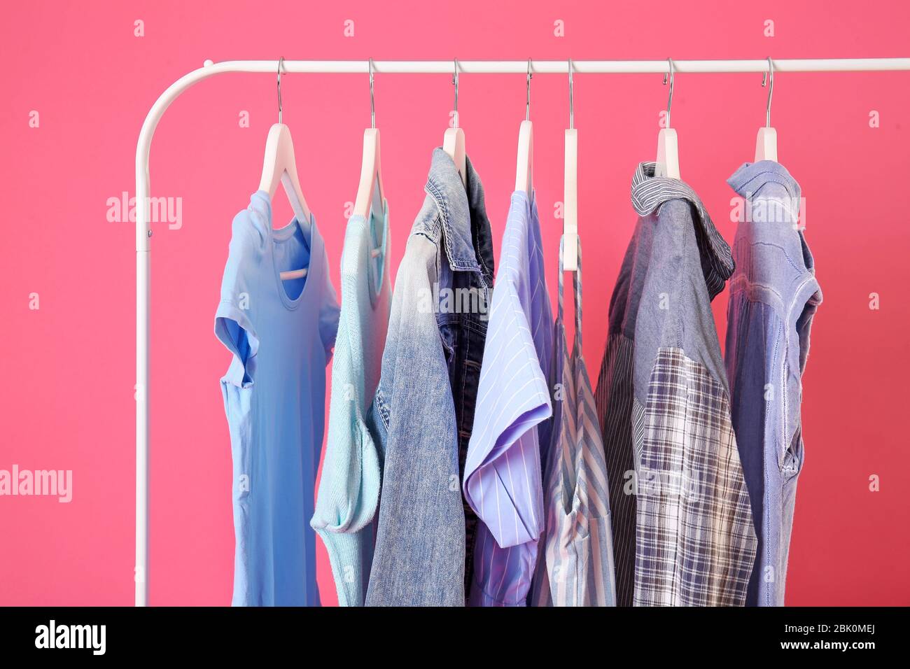 Rack with hanging clothes on color background Stock Photo - Alamy