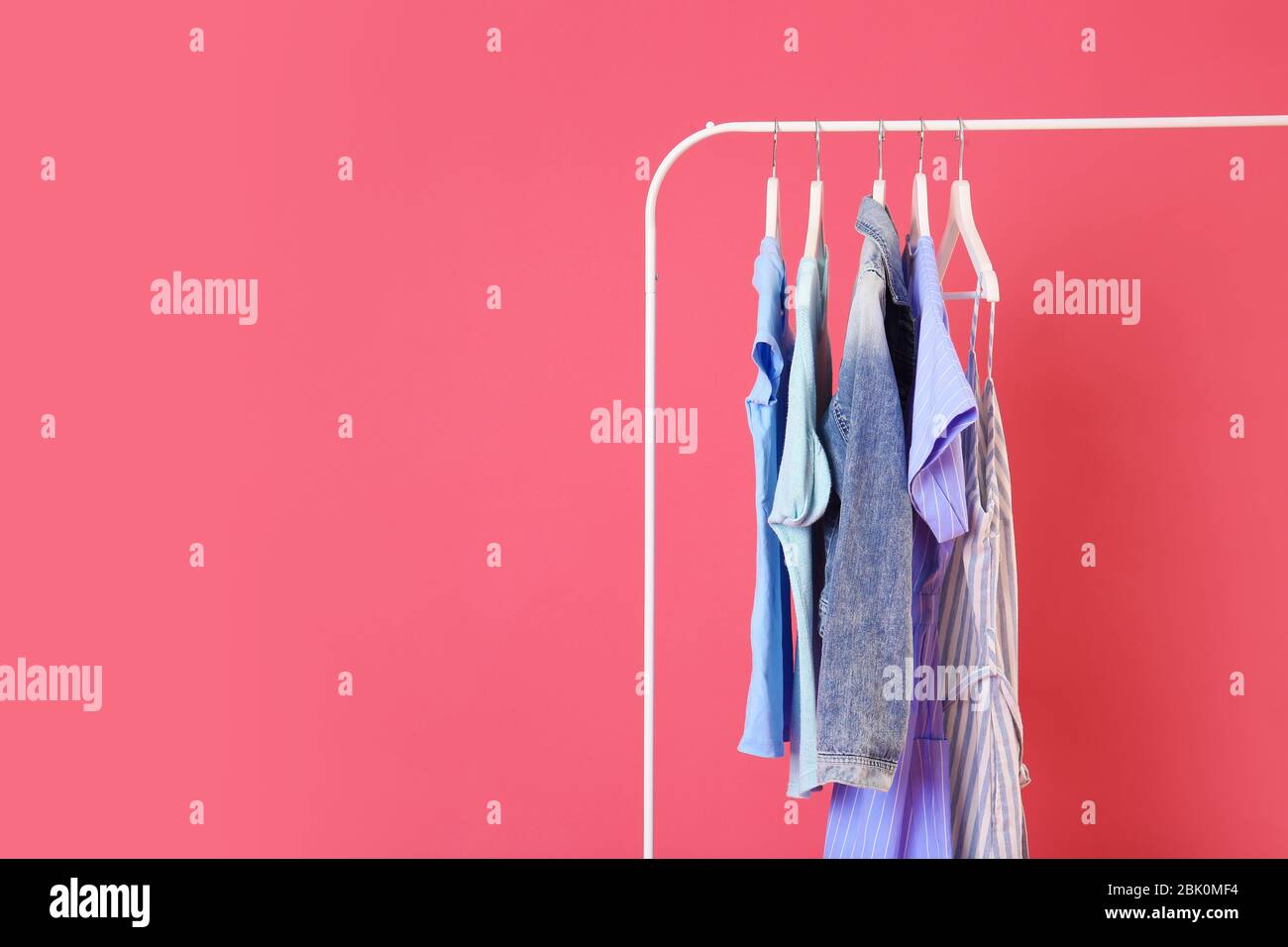 Rack with hanging clothes on color background Stock Photo - Alamy