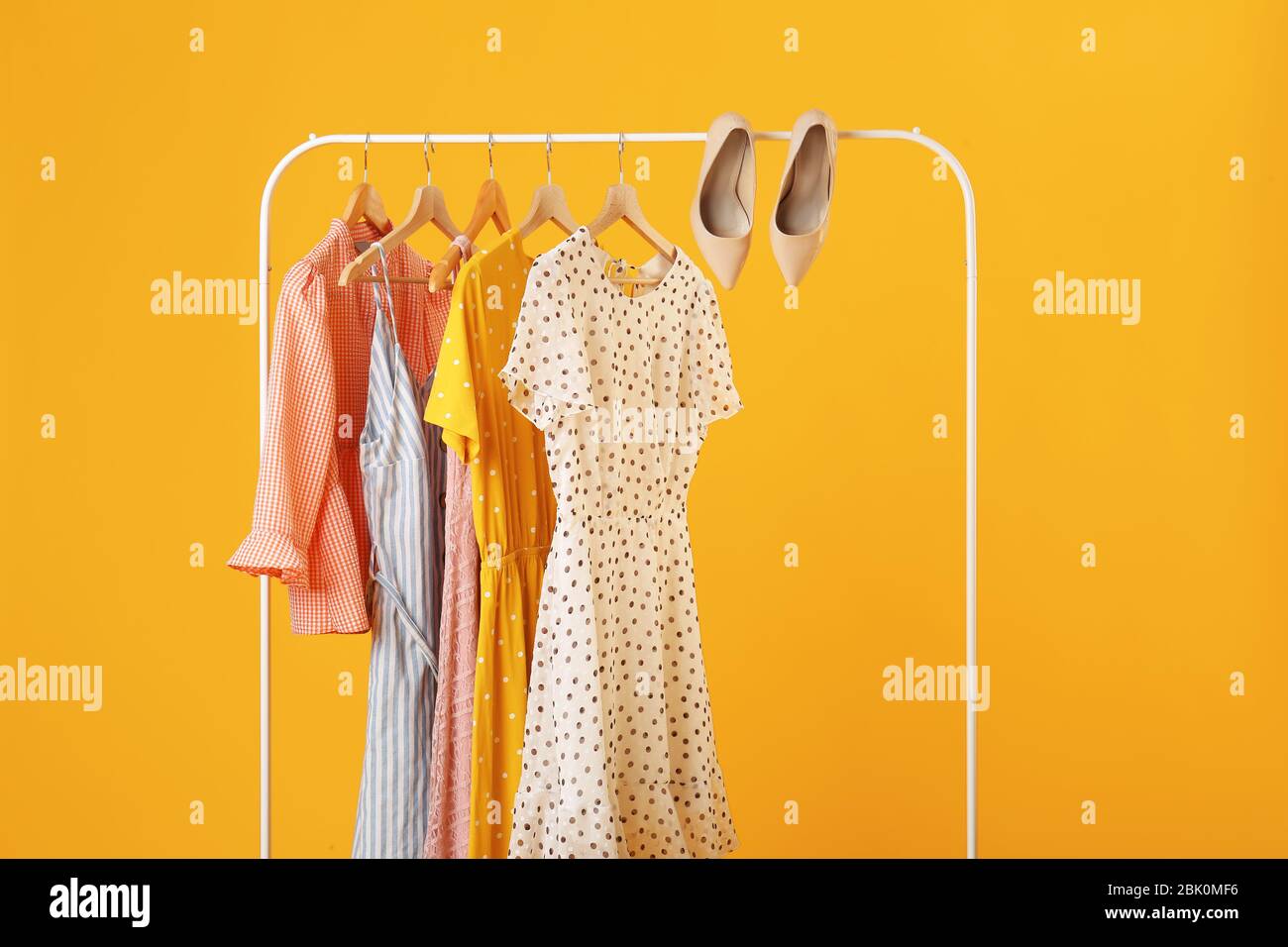 Rack with hanging clothes on color background Stock Photo - Alamy