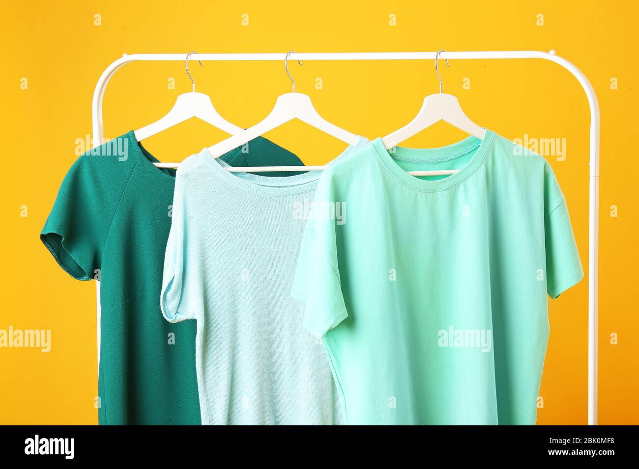 Rack with hanging clothes on color background Stock Photo - Alamy