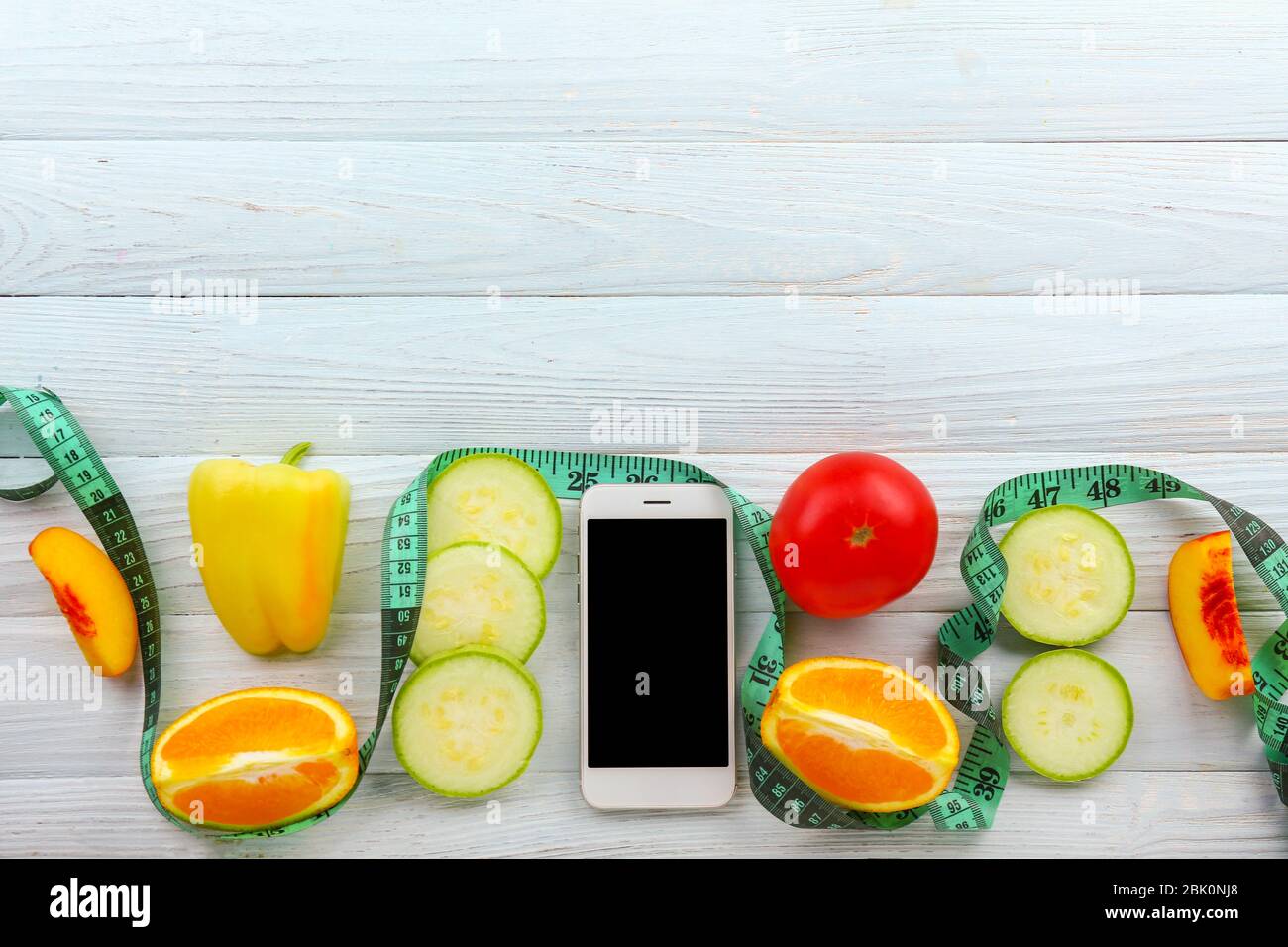 Modern mobile phone with fresh fruits, vegetables and measuring tape on ...