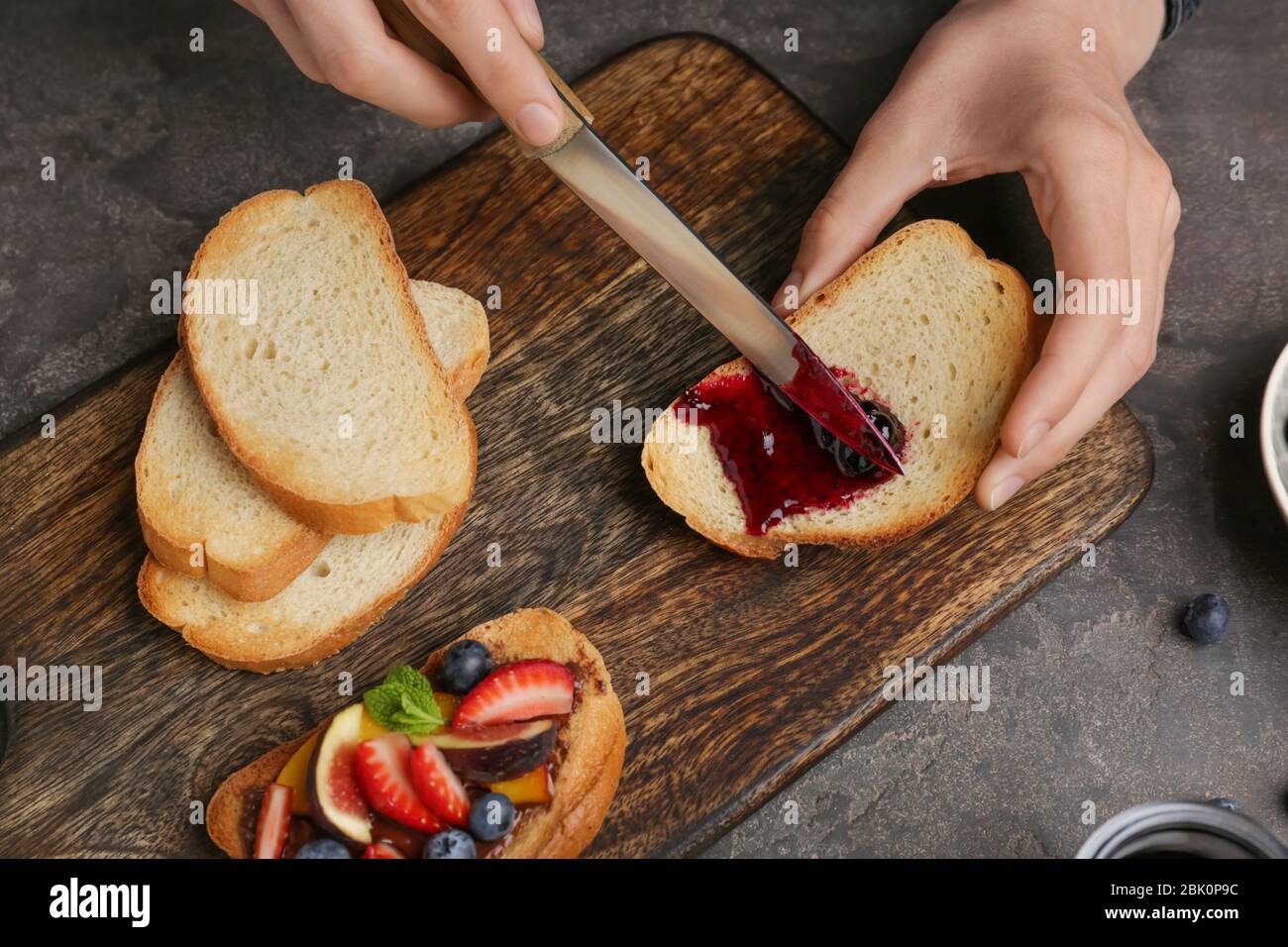 Woman spreading tasty berry jam onto toasted bread, closeup Stock Photo ...