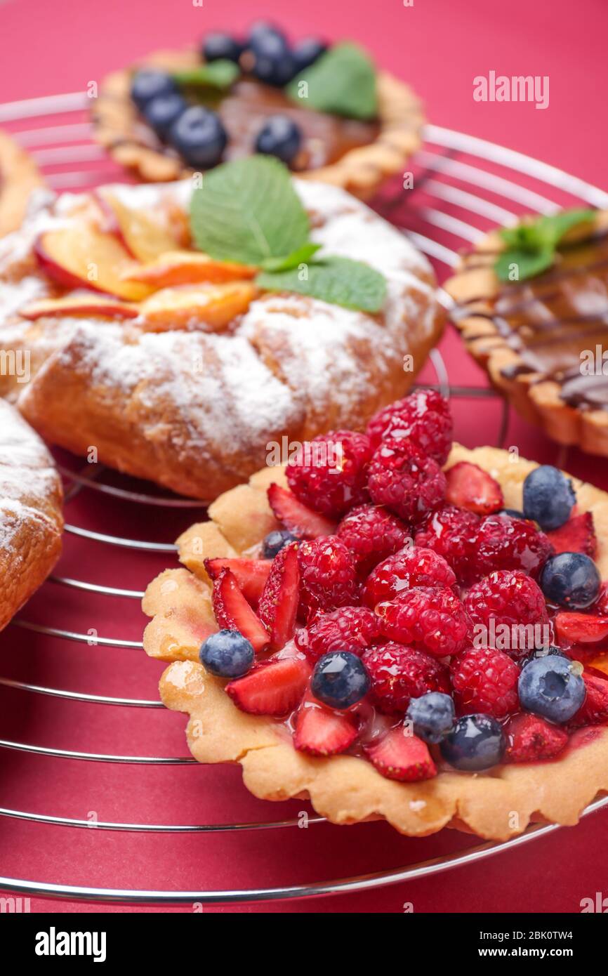 Rack with sweet cakes on color background, closeup Stock Photo - Alamy