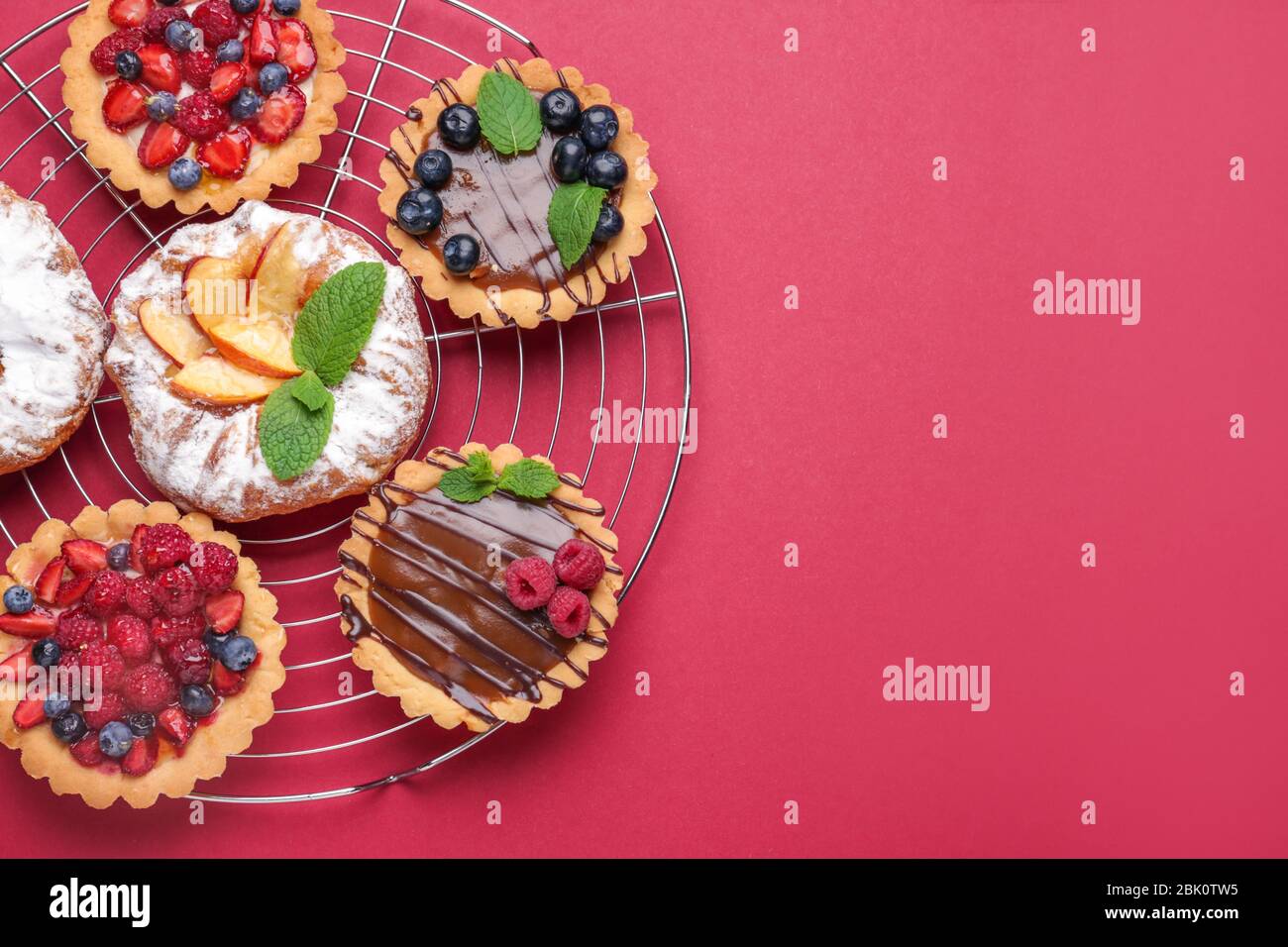 Rack with sweet cakes on color background Stock Photo - Alamy