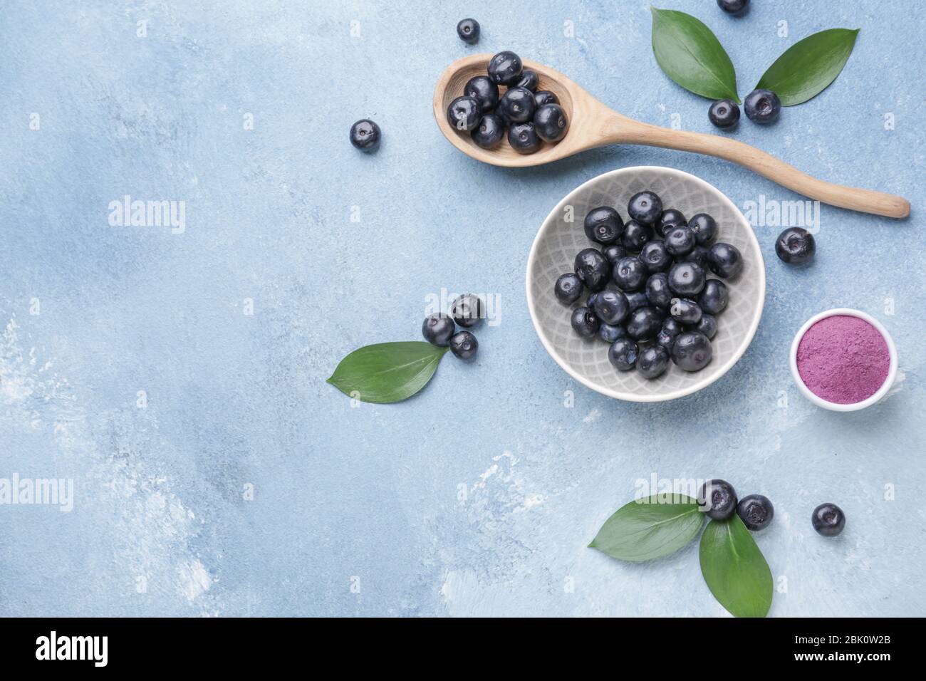Acai berries with powder on color background Stock Photo - Alamy