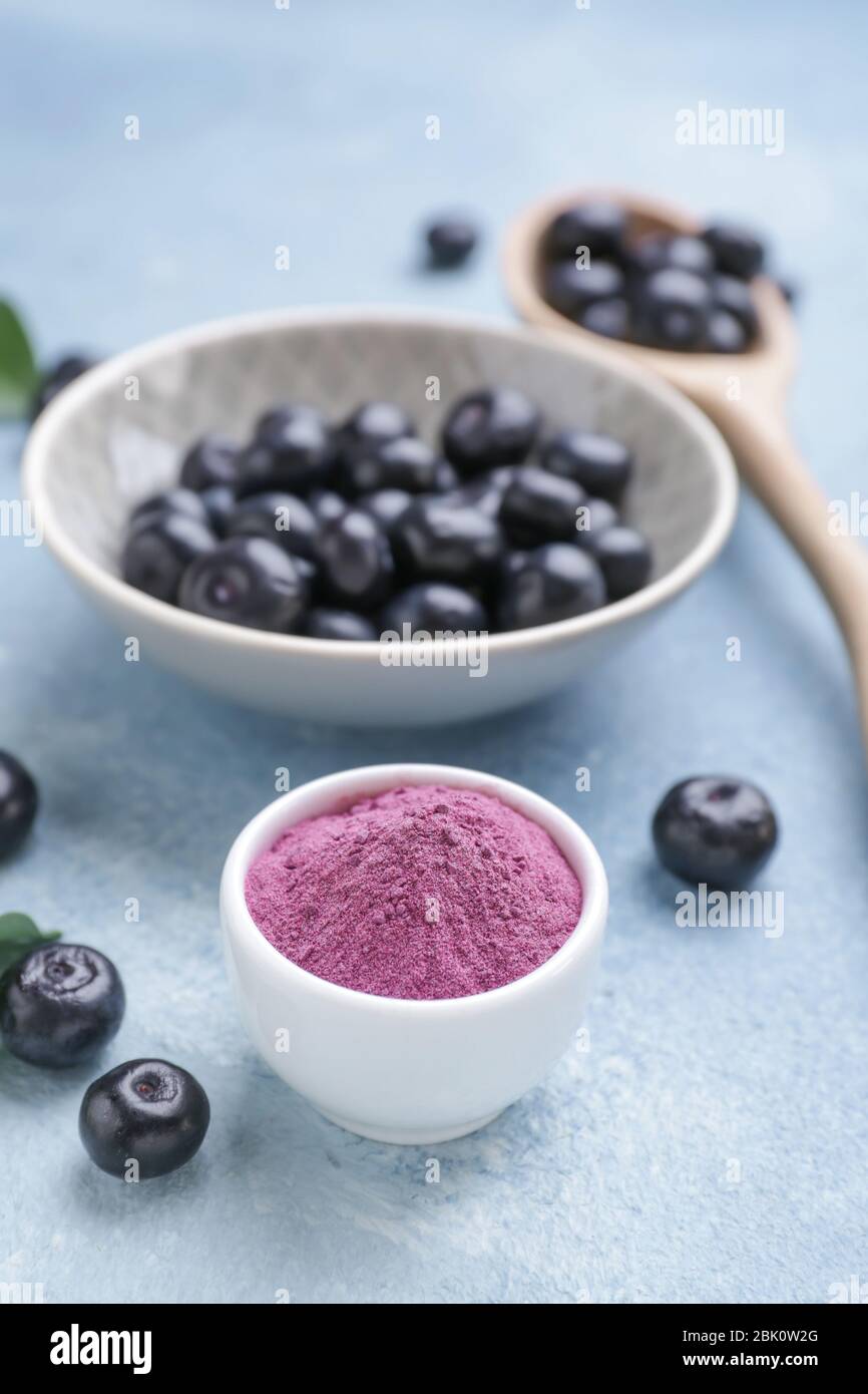 Acai berries with powder on color background Stock Photo - Alamy