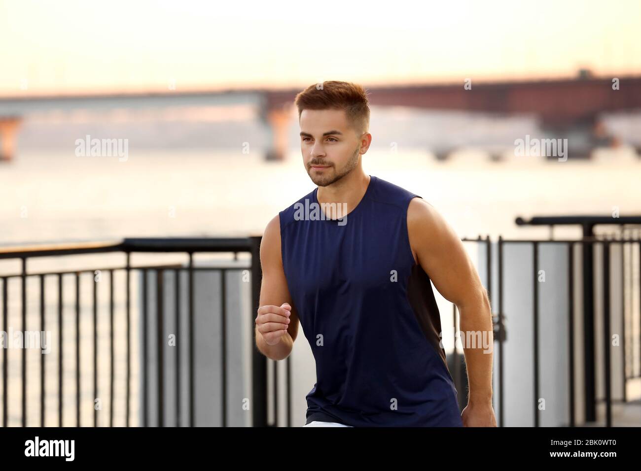 Handsome sporty man running near river Stock Photo - Alamy