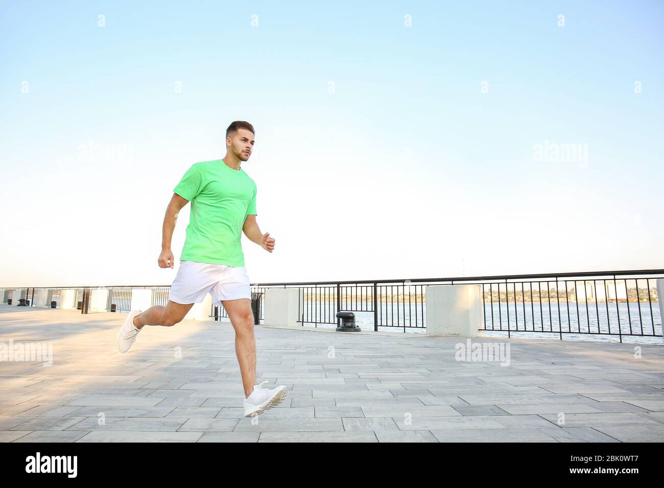 Handsome sporty man running near river Stock Photo - Alamy