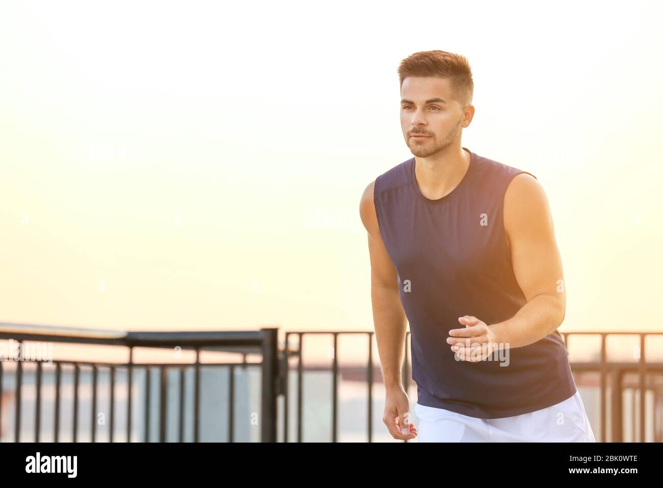 Handsome sporty man running near river Stock Photo - Alamy