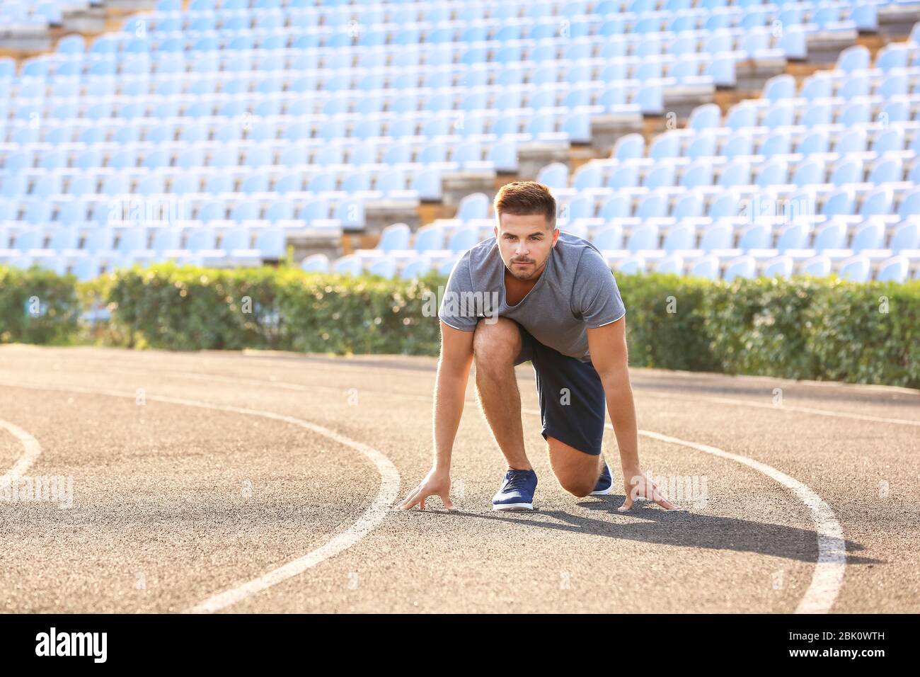 Sporty man in crouch start position at the stadium Stock Photo - Alamy