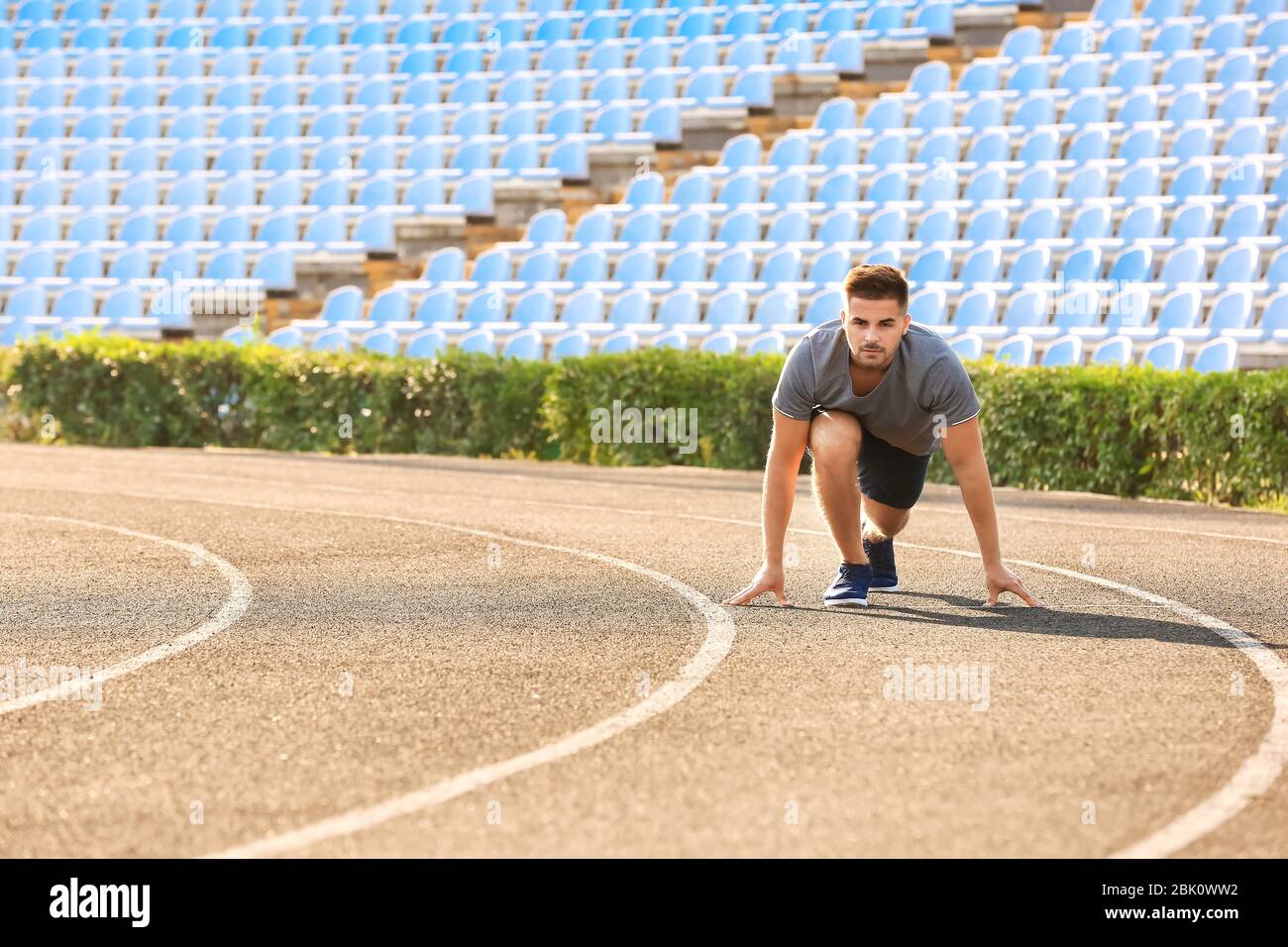 Sporty man in crouch start position at the stadium Stock Photo - Alamy