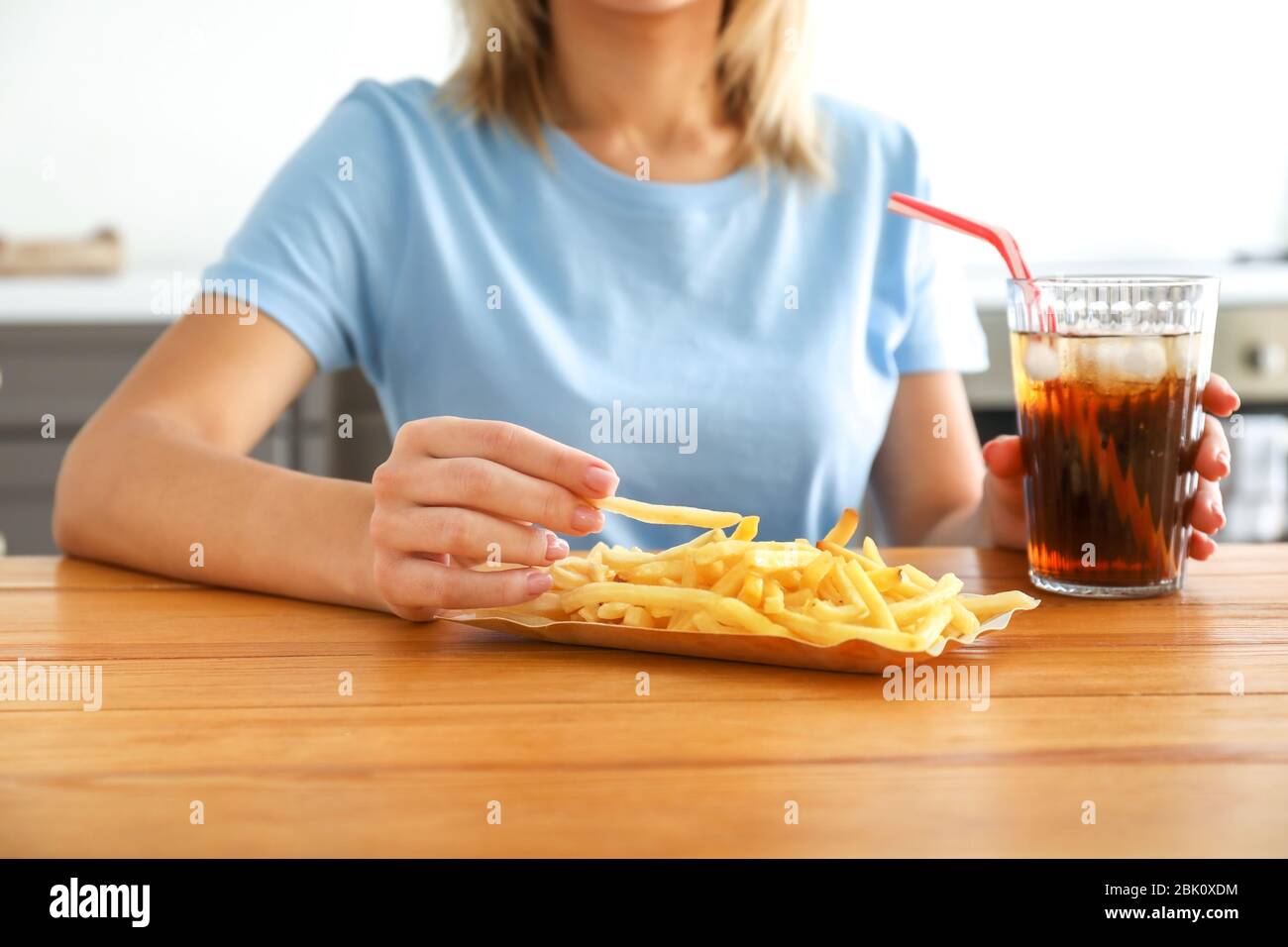 Woman with glass of cold cola and french fries at table Stock Photo - Alamy