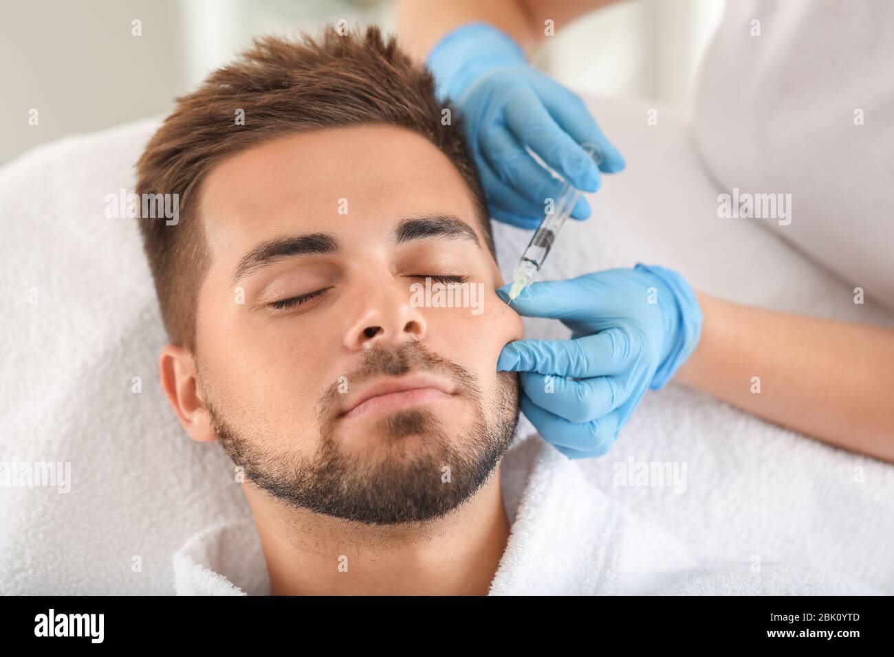 Handsome man receiving filler injection in beauty salon Stock Photo - Alamy