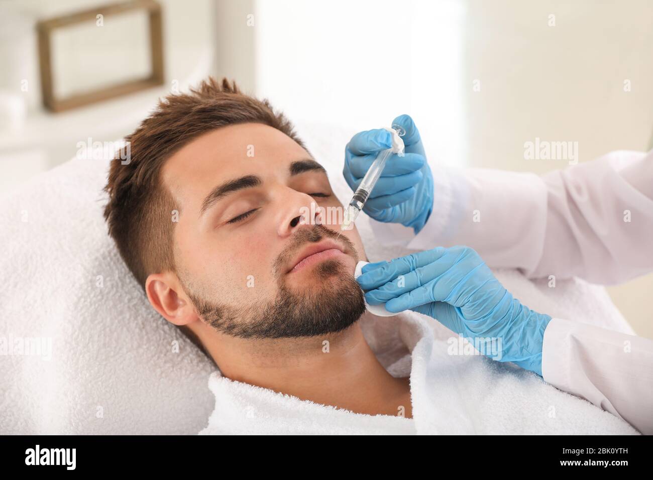 Handsome man receiving filler injection in beauty salon Stock Photo - Alamy