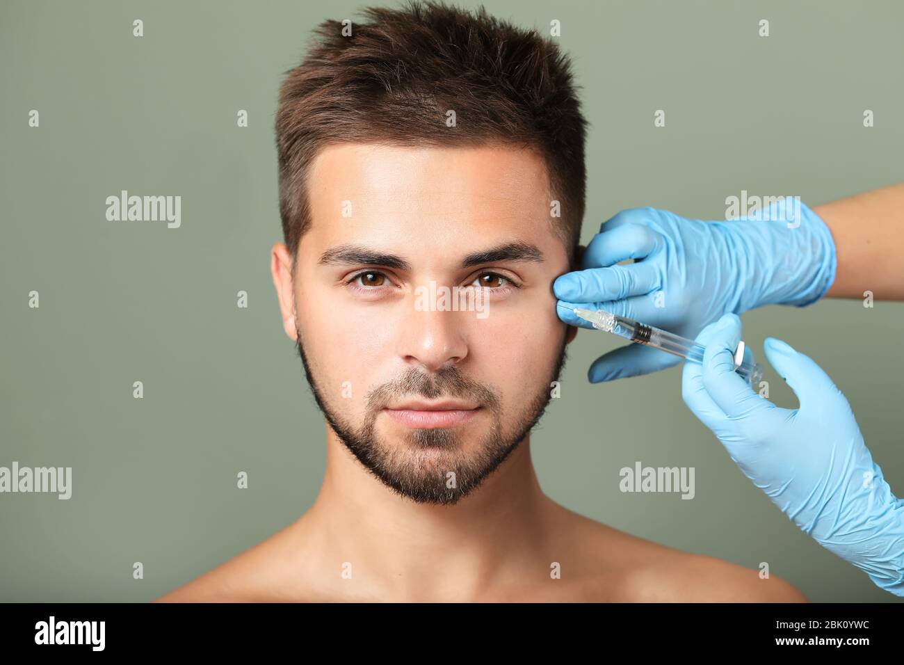 Handsome man receiving filler injection on color background Stock Photo ...