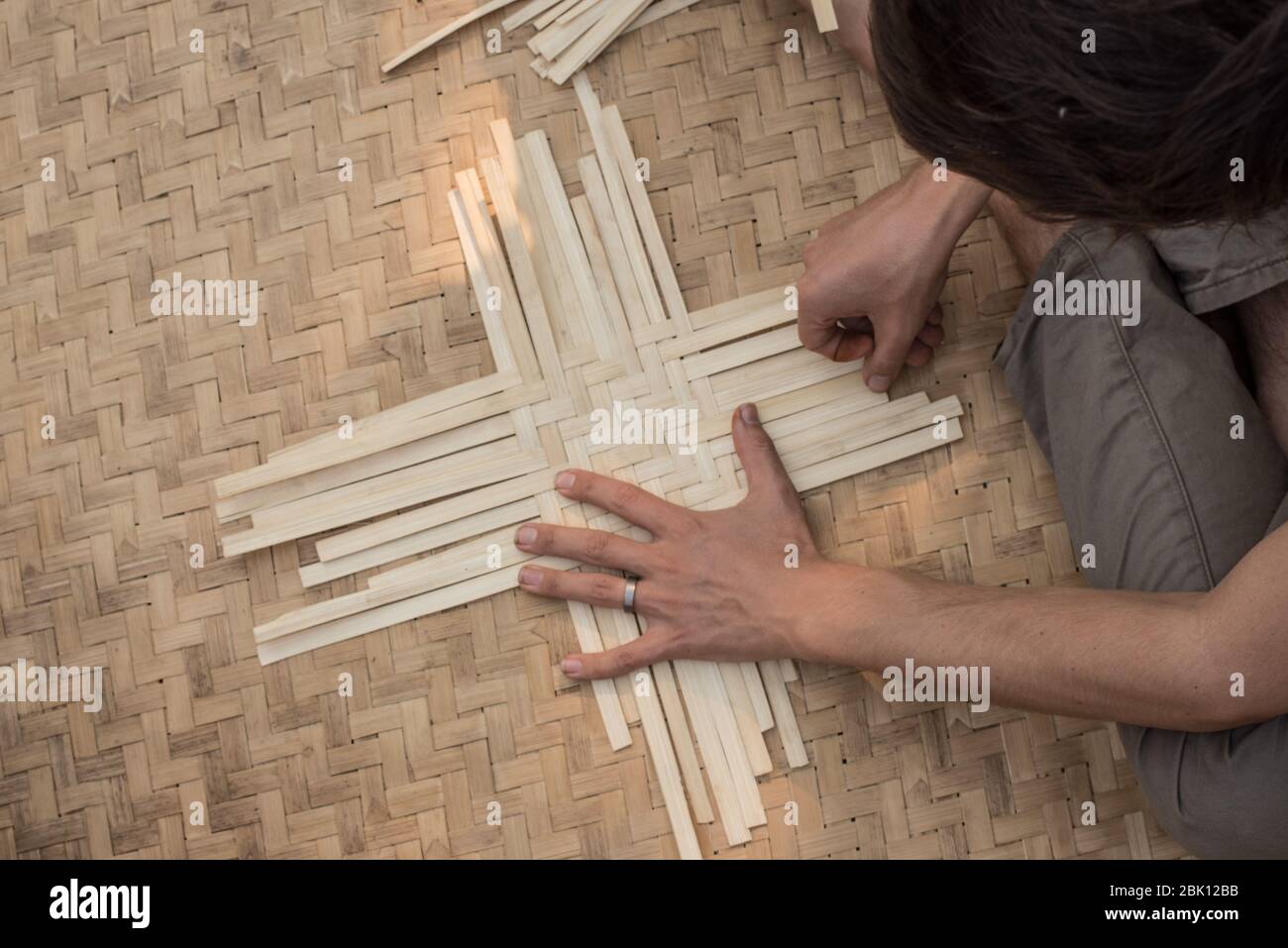 Two hands weaving a bamboo pattern, a traditional craft in Laos, during ...