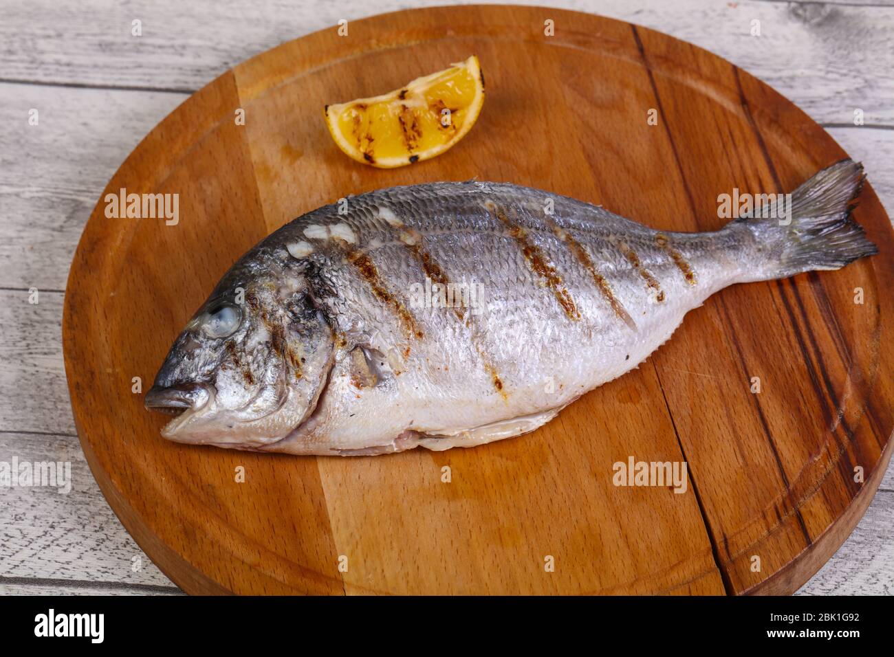 Grilled dorada with lemon over the wooden board Stock Photo - Alamy