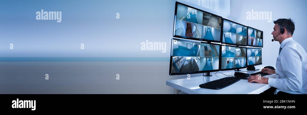 Security System Operator Looking At CCTV Camera Footage On Computer ...