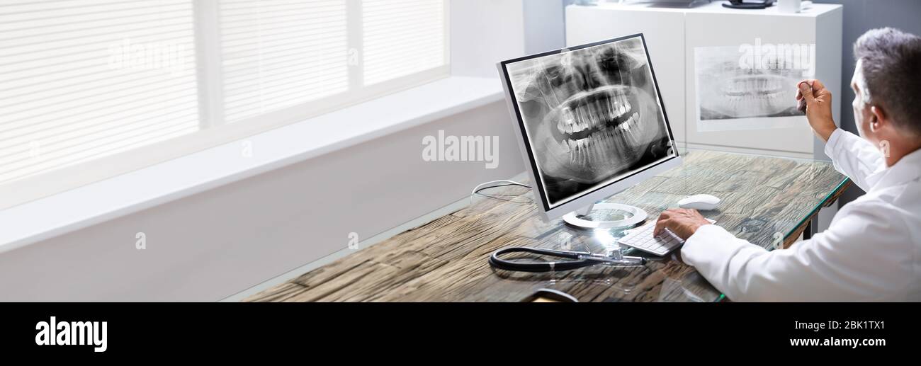 Dentist Using Oral Software Looking At Teeth Xray On Desktop Computer ...